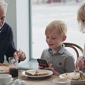 Restaurant, breakfast with grandparents and grandson using his phone in ...